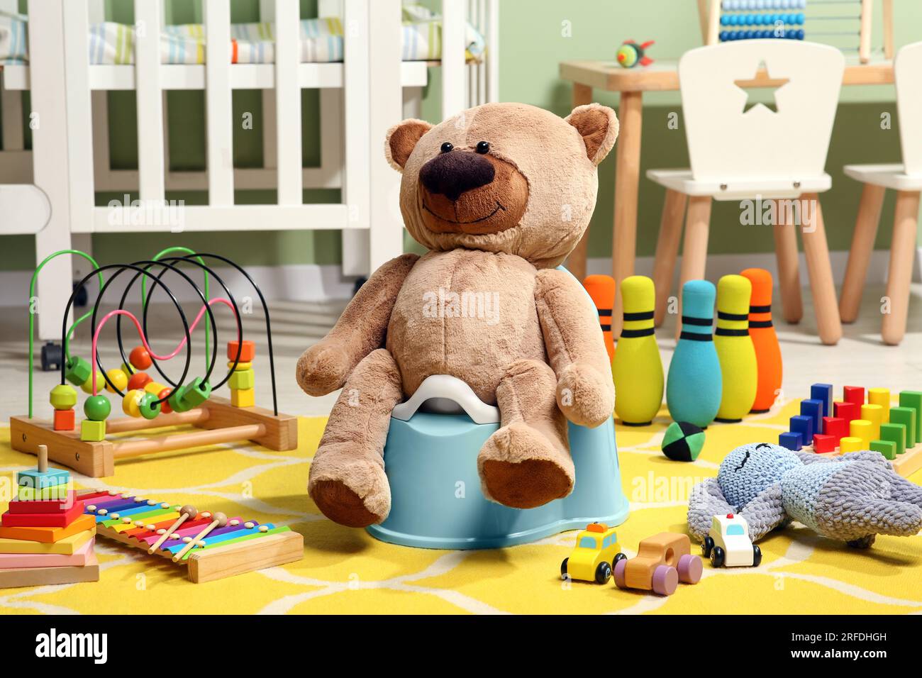Teddy bear on light blue baby potty and many other toys in room. Toilet ...