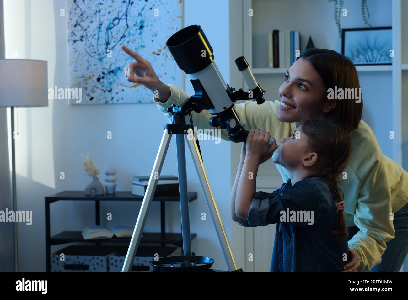 Happy mother and her cute daughter using telescope to look at stars in ...