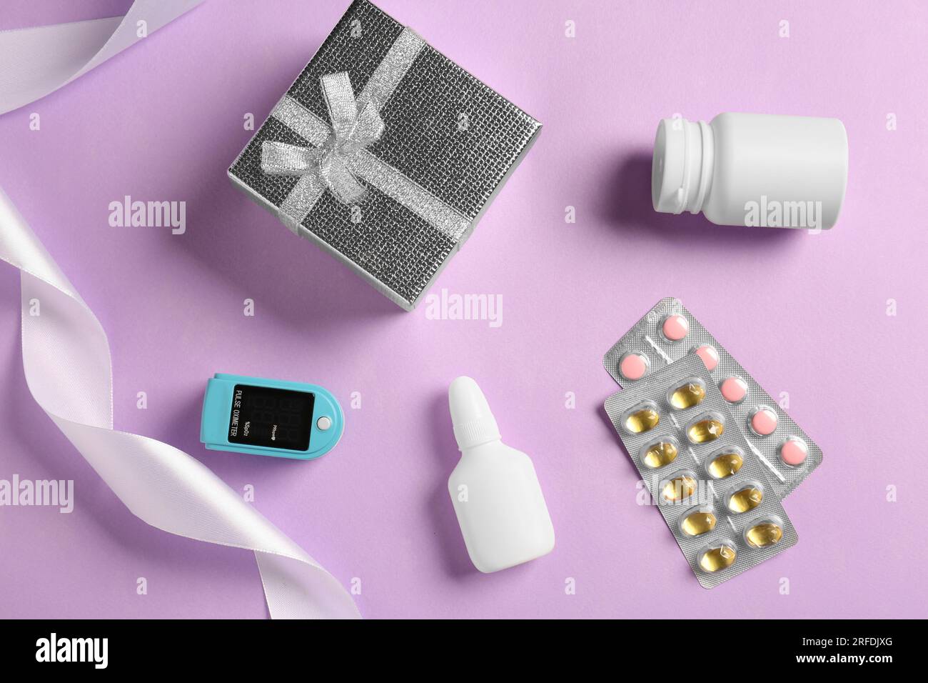 Spray bottle, pills, box and fingertip pulse oximeter on violet ...