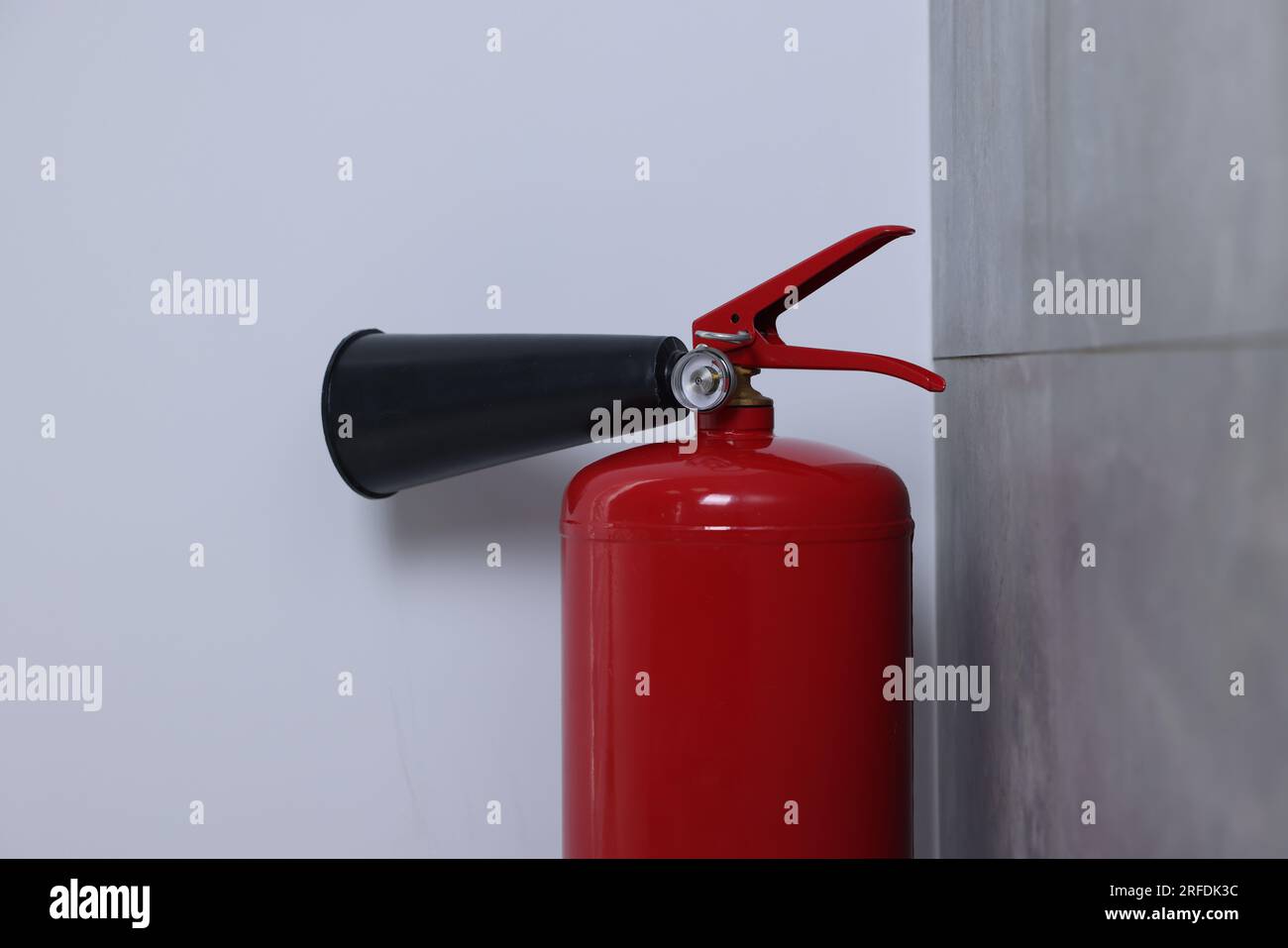 One red fire extinguisher in corner indoors Stock Photo - Alamy