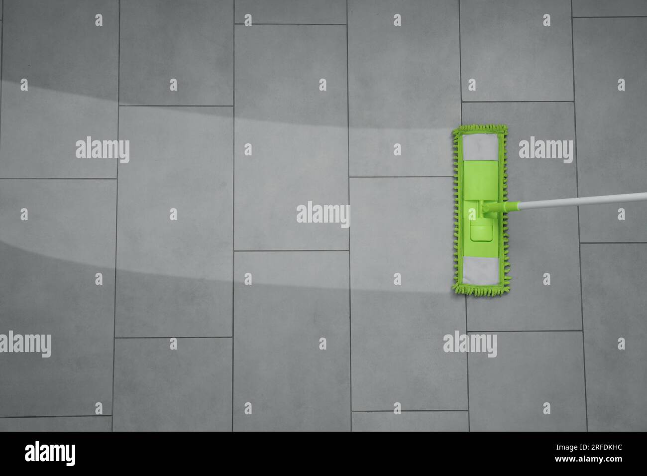 Washing floor with mop indoors, top view. Clean trace on dirty surface ...