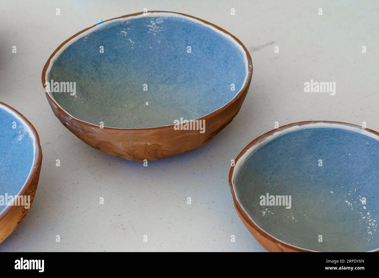 Three handmade brown and red terra cotta clay bowls with blue glaze on ...