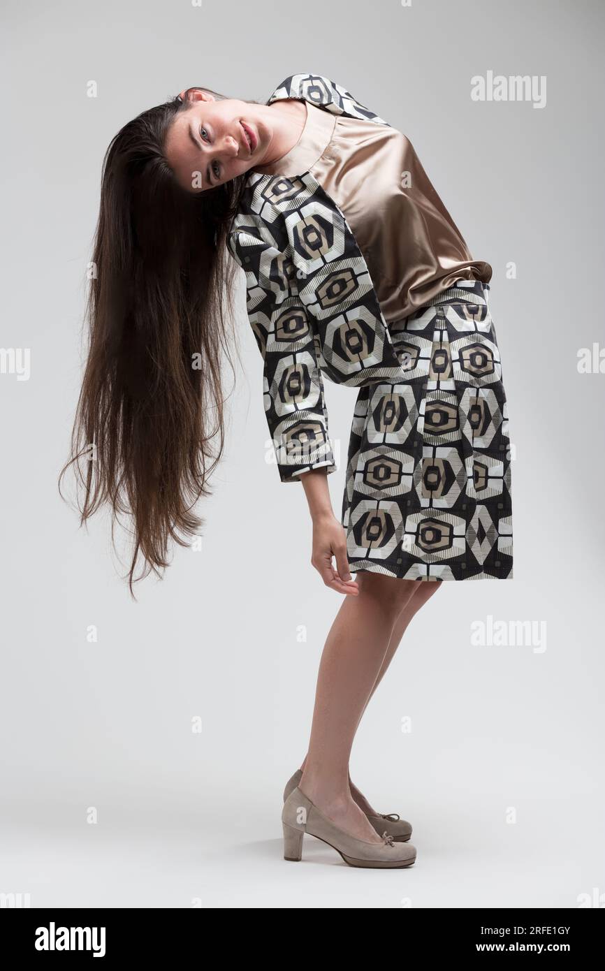 Fashion model with long hair to her knees, bends her flexible back ...