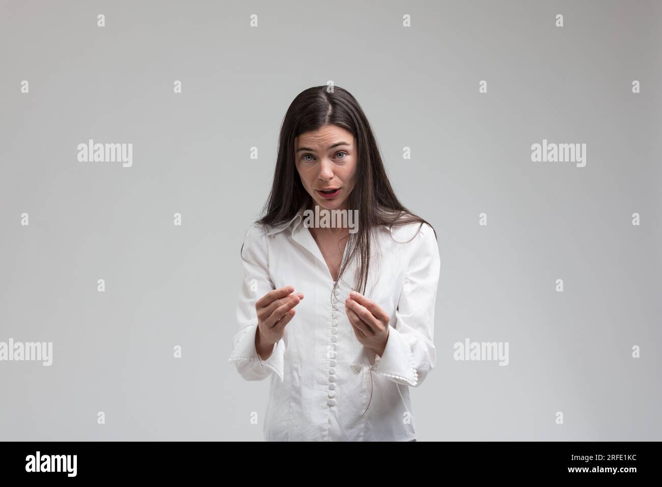 In a white shirt, a beautiful woman with long hair uses Italian ...