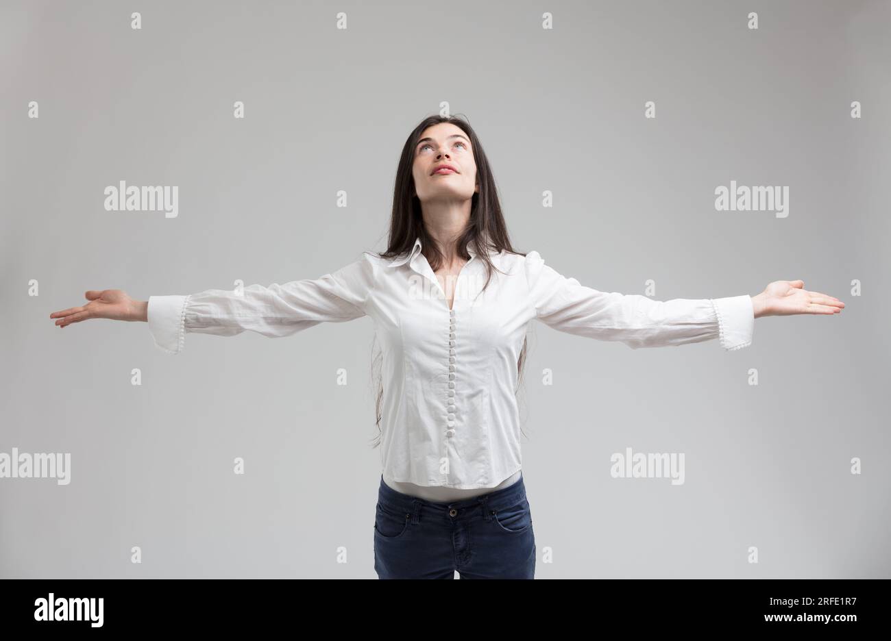 beautiful woman in white, with long hair, opens her arms wide, thanking ...