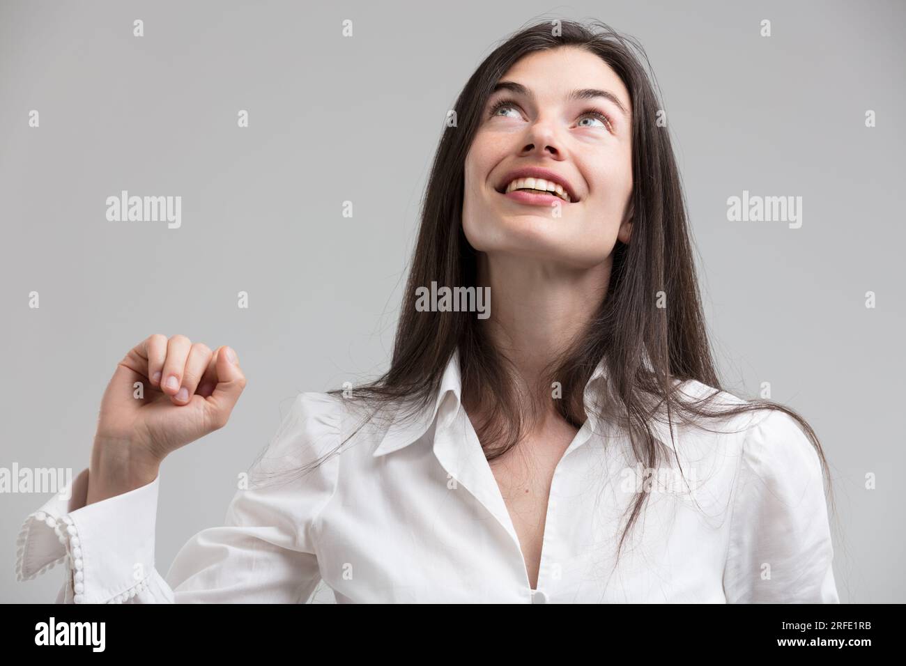Woman with long hair and fair skin looks upward, thinking. Using her ...