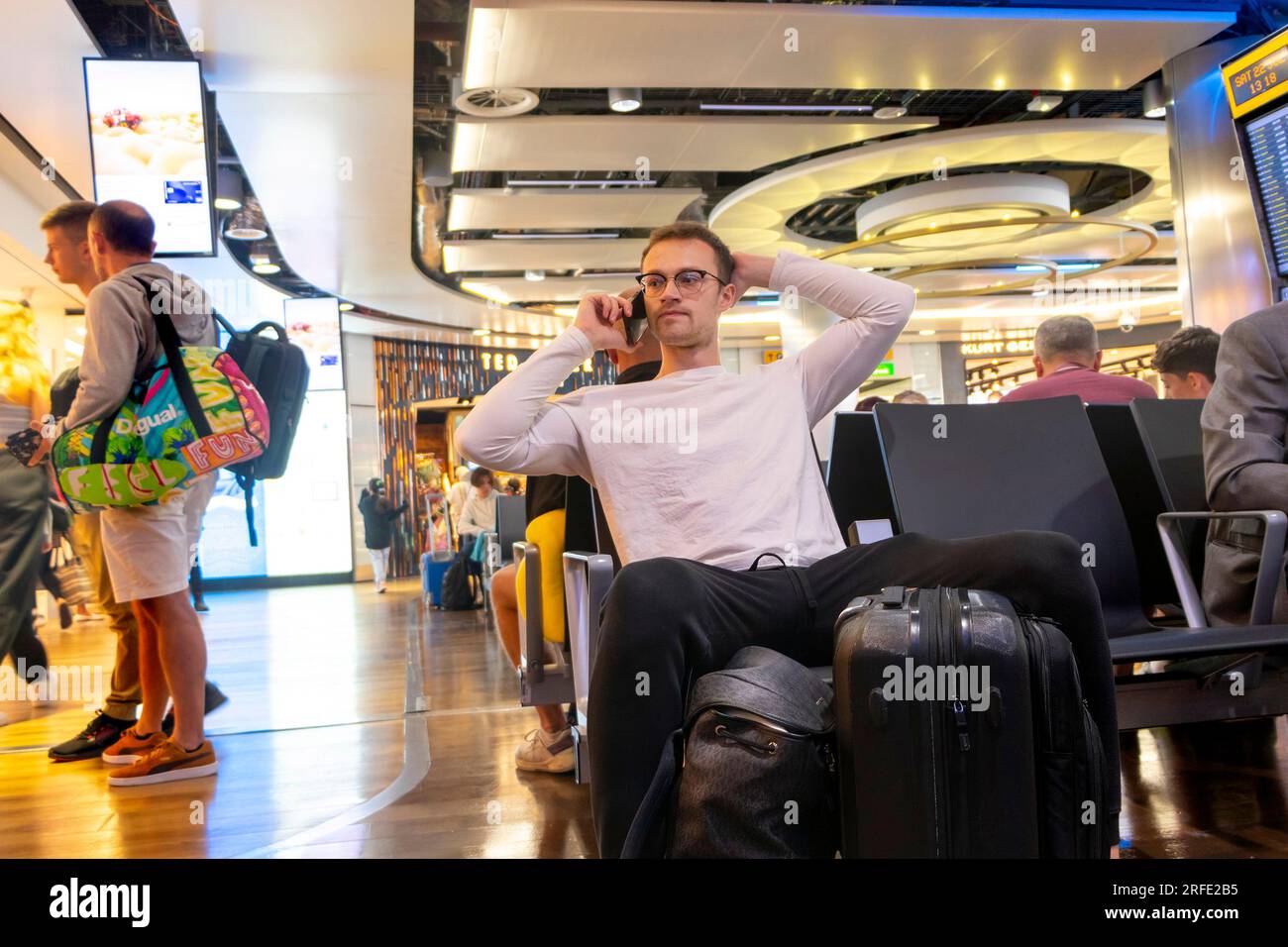 man on mobile cell phone waiting in departure lounge at London Heathrow ...