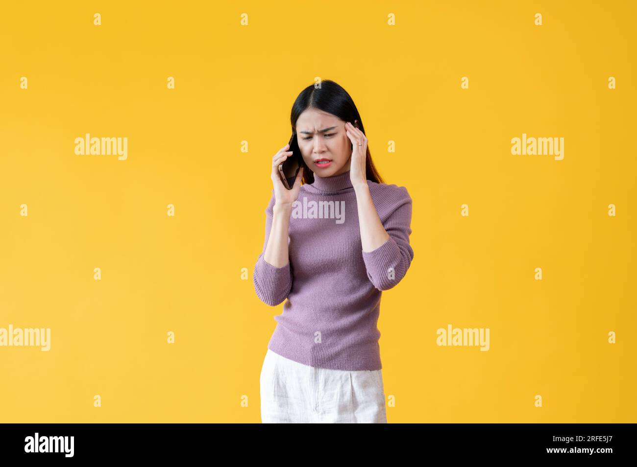 A stressed and dissatisfied Asian woman is talking on the phone with ...