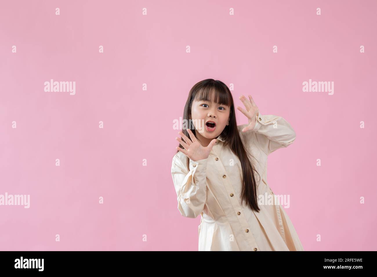 A cheerful and adorable little Asian girl in a cute dress standing ...