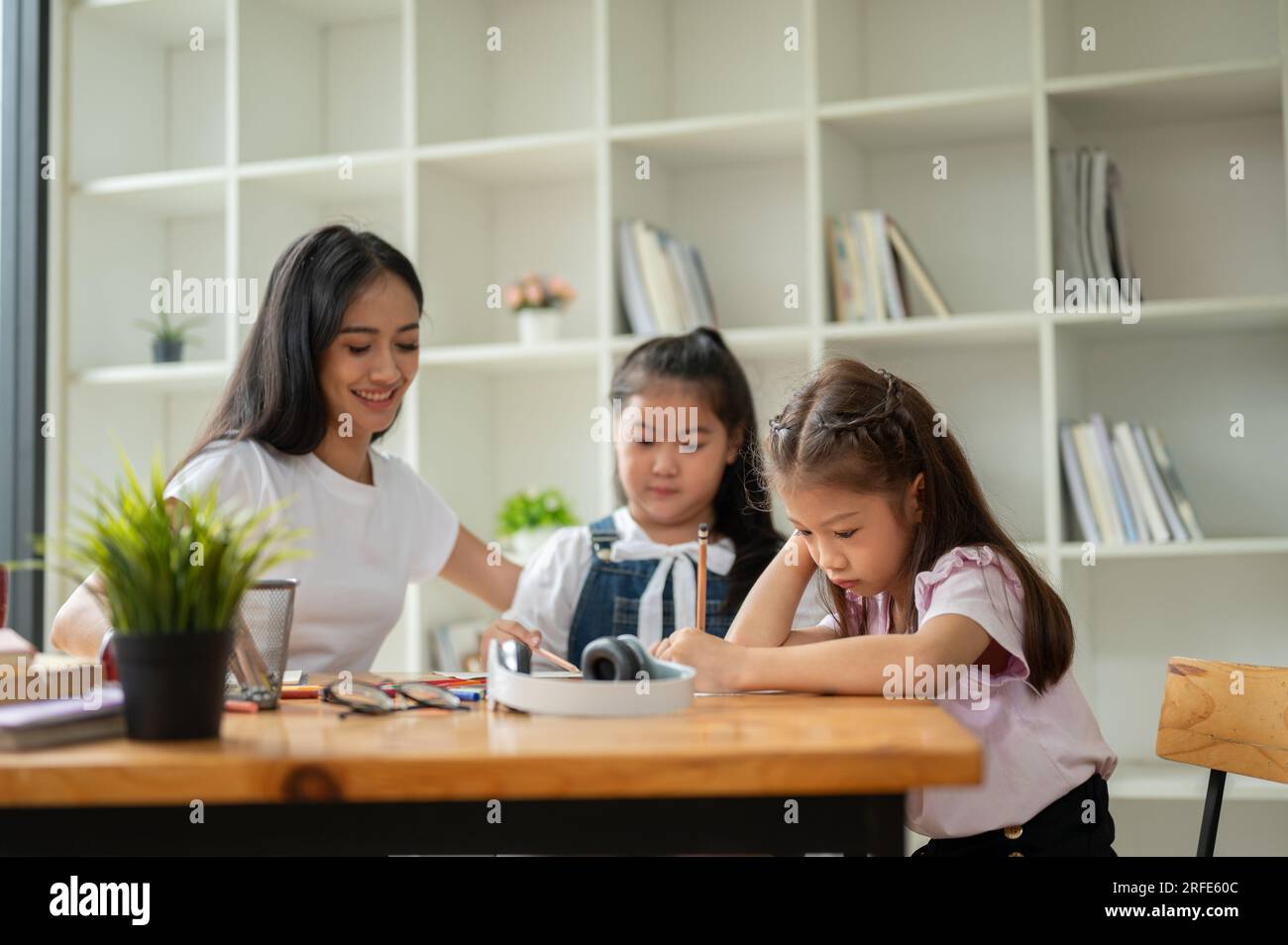 A focused young Asian elementary school girl is studying with a private ...