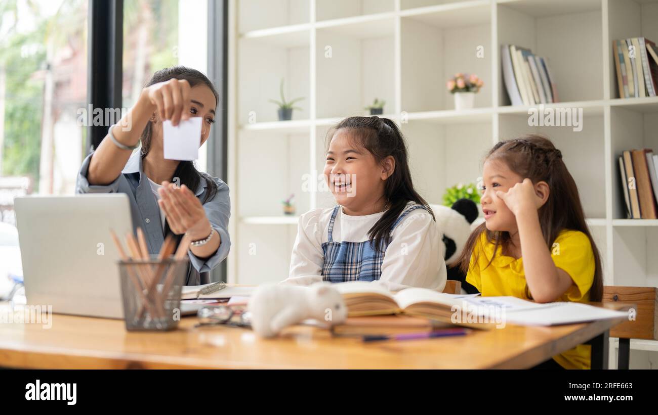 Two adorable young Asian girls are enjoying studying English with a ...