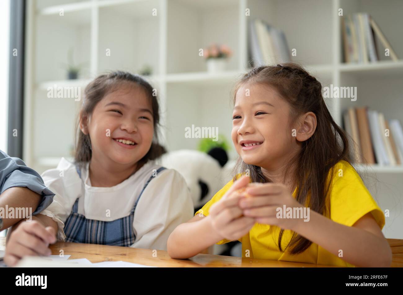 Two adorable young Asian girls are enjoying talking on a small break in ...