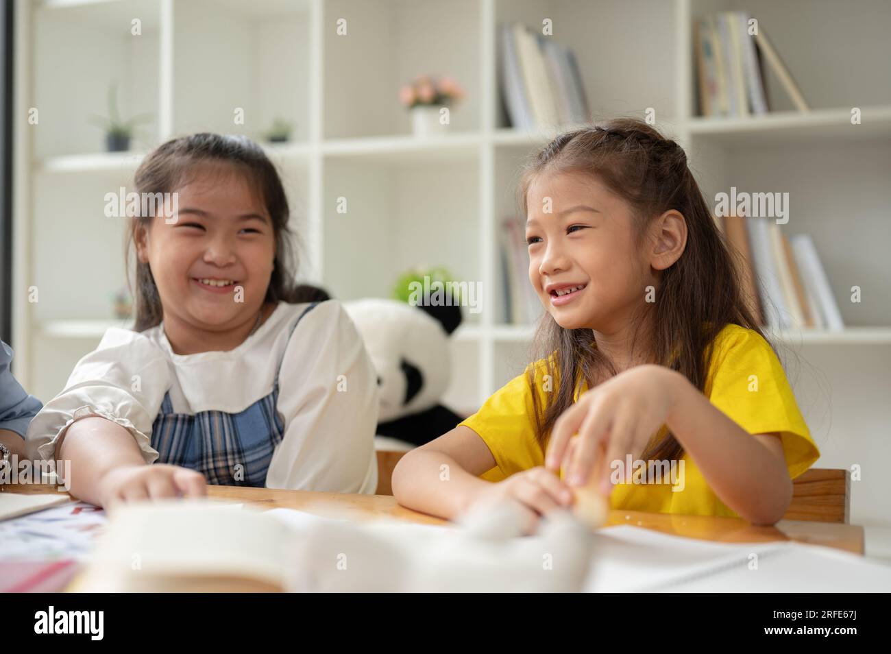 Two adorable young Asian girls are enjoying talking on a small break in ...