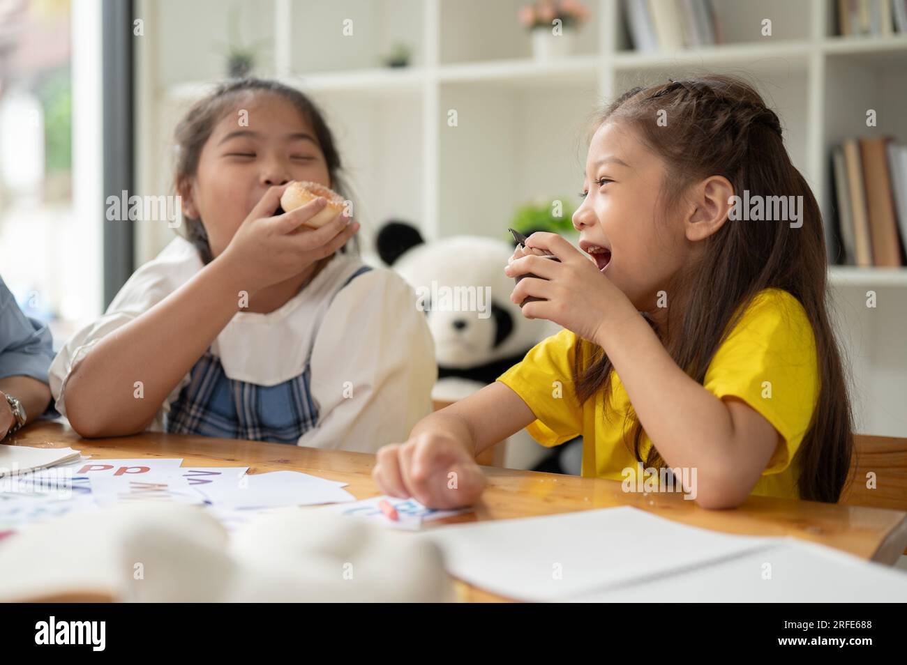 Two adorable young Asian girls are enjoying talking and eating ...