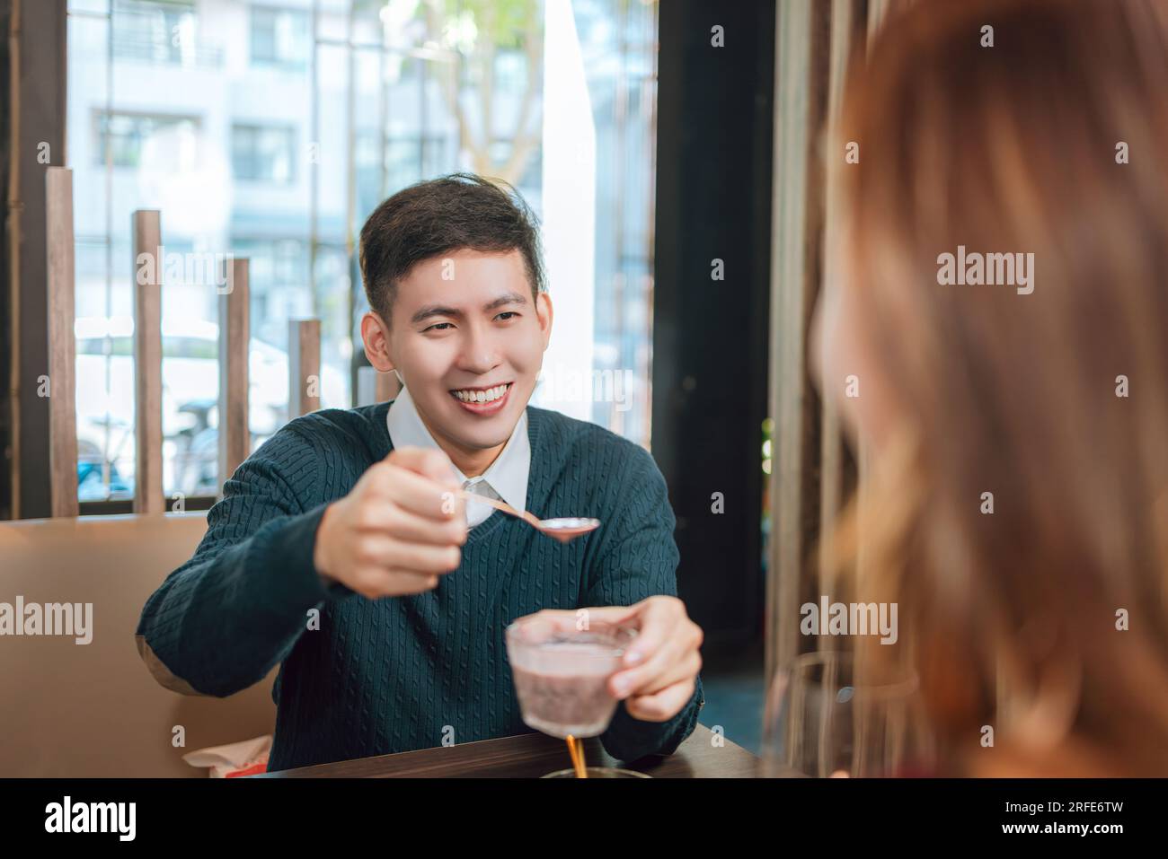 Young Asian Man Feeding Happy Girlfriend With Tasty Food In Restaurant