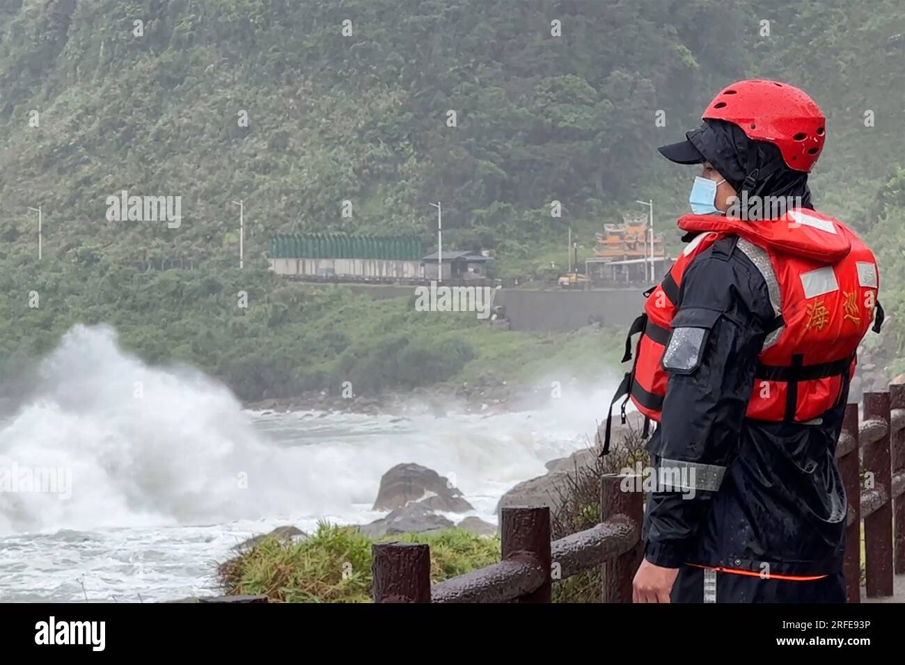 A coast guard officer watches as waves crash on the shore ahead of ...