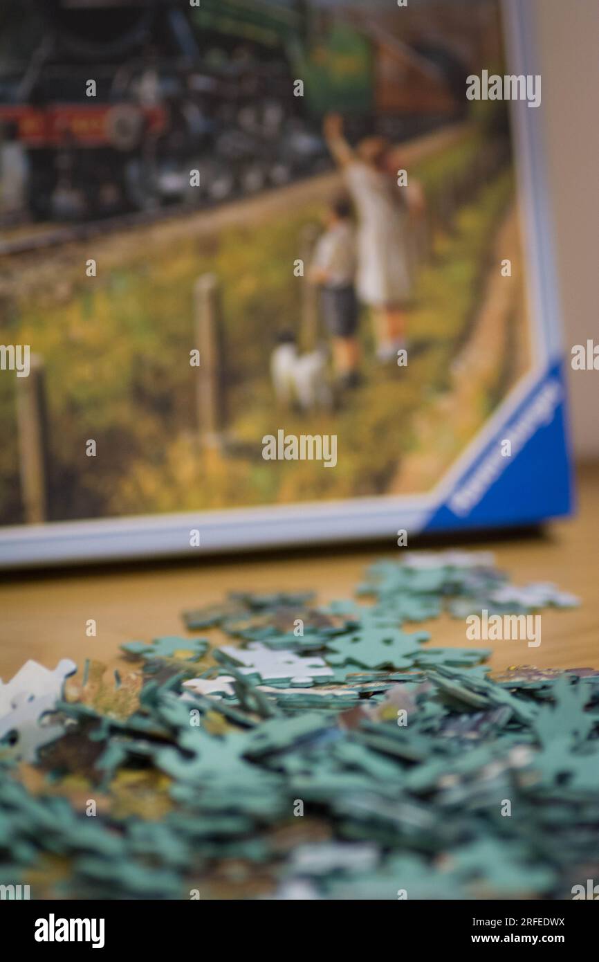 Pieces of a jigsaw puzzle next to the puzzle box top Stock Photo - Alamy