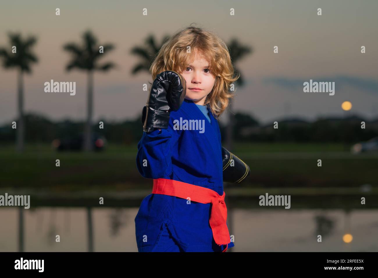 Kid boy in kimono practicing judo, taekwondo, jujitsu, kung-fu, jiu-jitsu, aikido outdoor. Sport ...