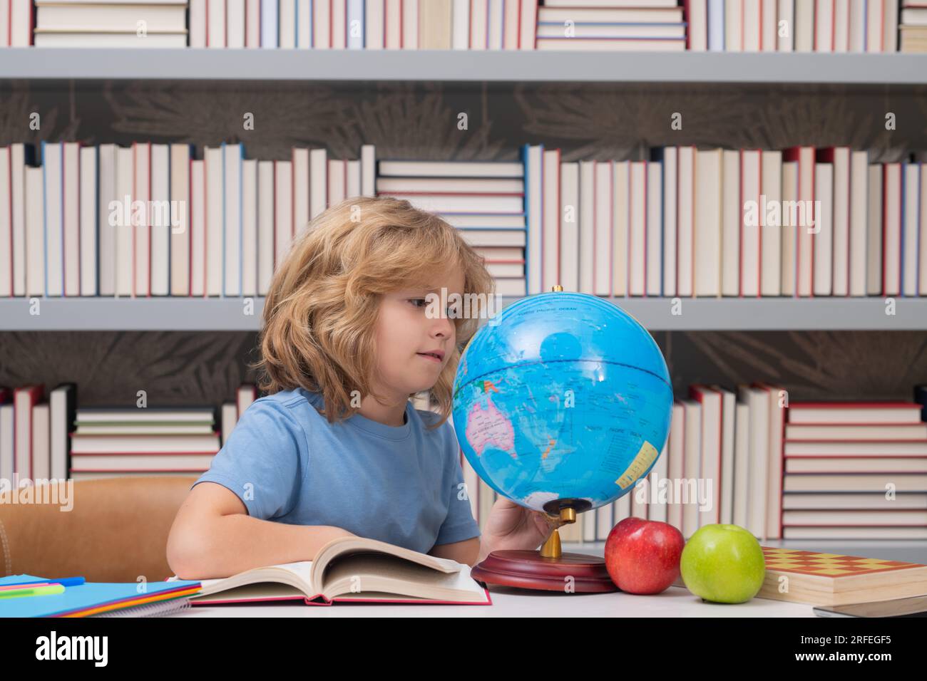 School pupil looking at globe in library, geography lesson. School ...