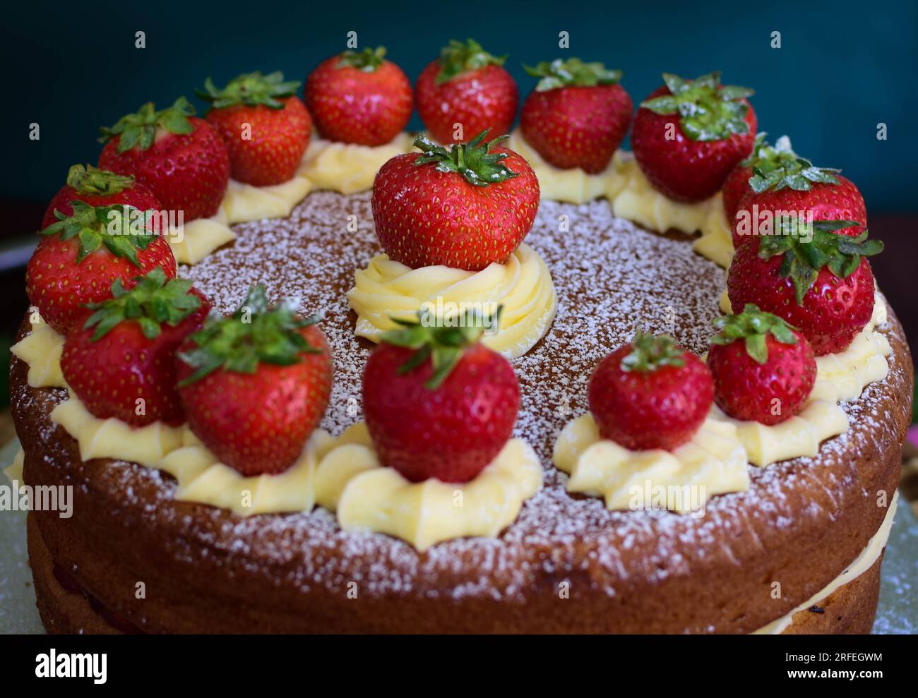 Decadent Victoria sponge cake topped with strawberries, vanilla icing ...