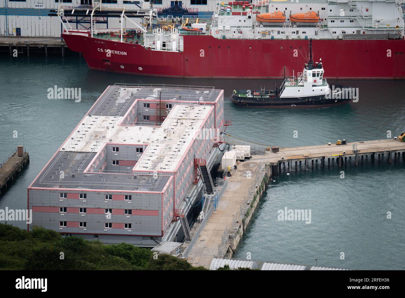 A tug boat passes the Bibby Stockholm accommodation barge at Portland ...