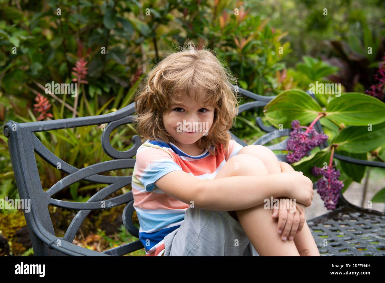 Kid sit on bench. Lifestyle portrait of funny kid outdoors. Summer kids ...