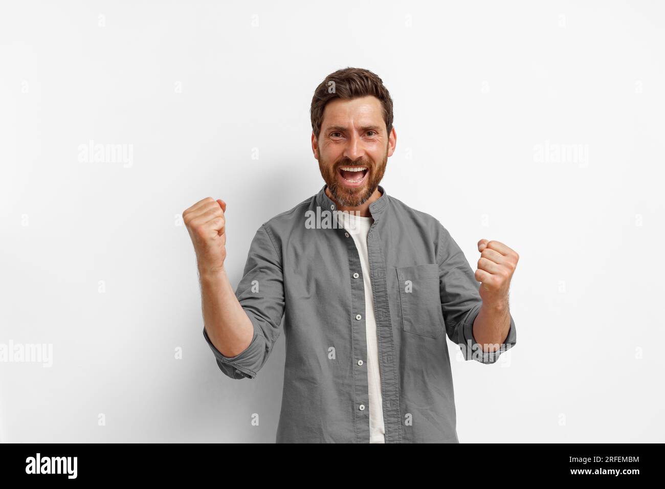 Emotional smiling male fan is standing on white background and ...