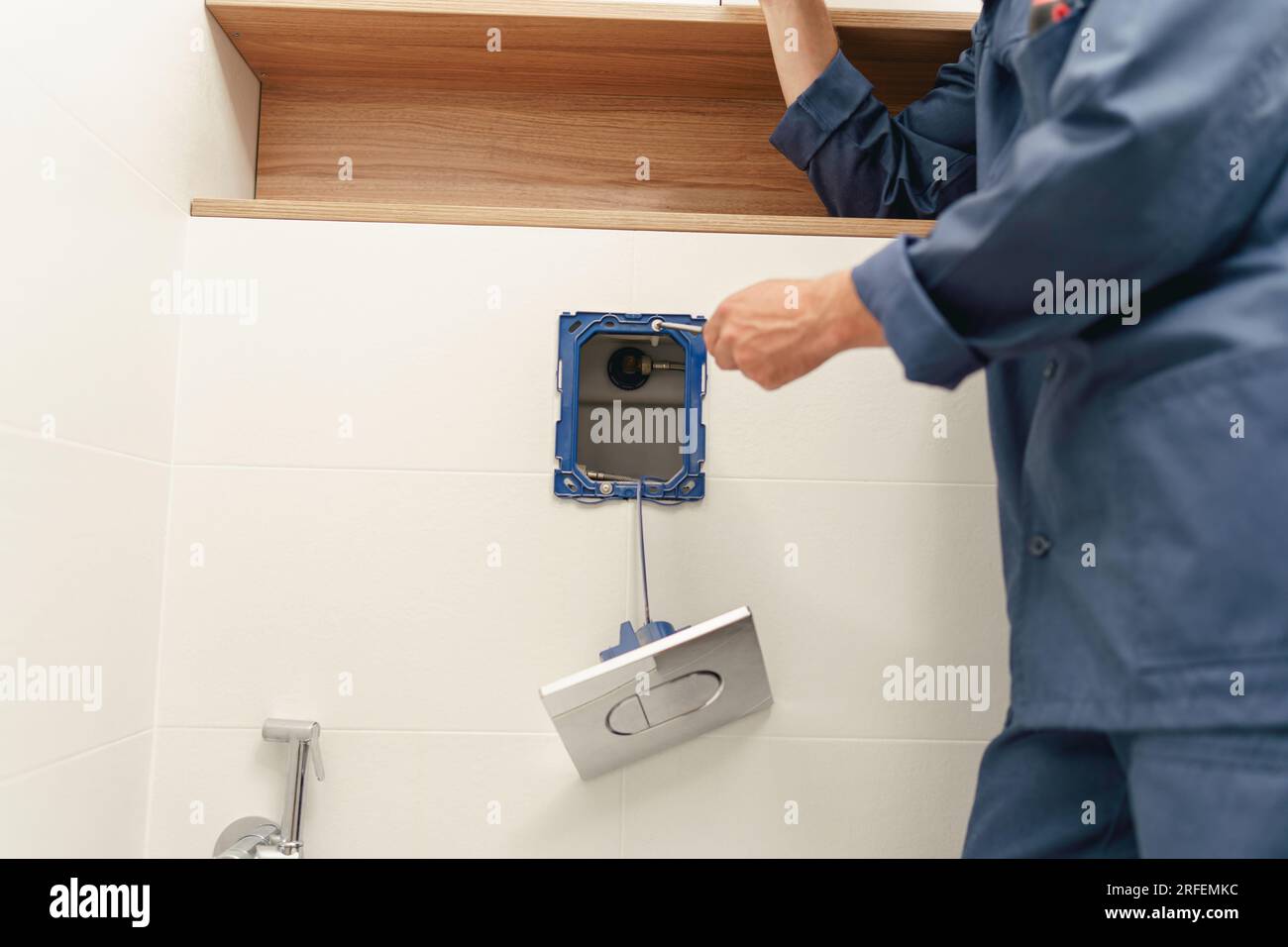 Repairman holding screwdriver tool while installing toilet flush panel ...