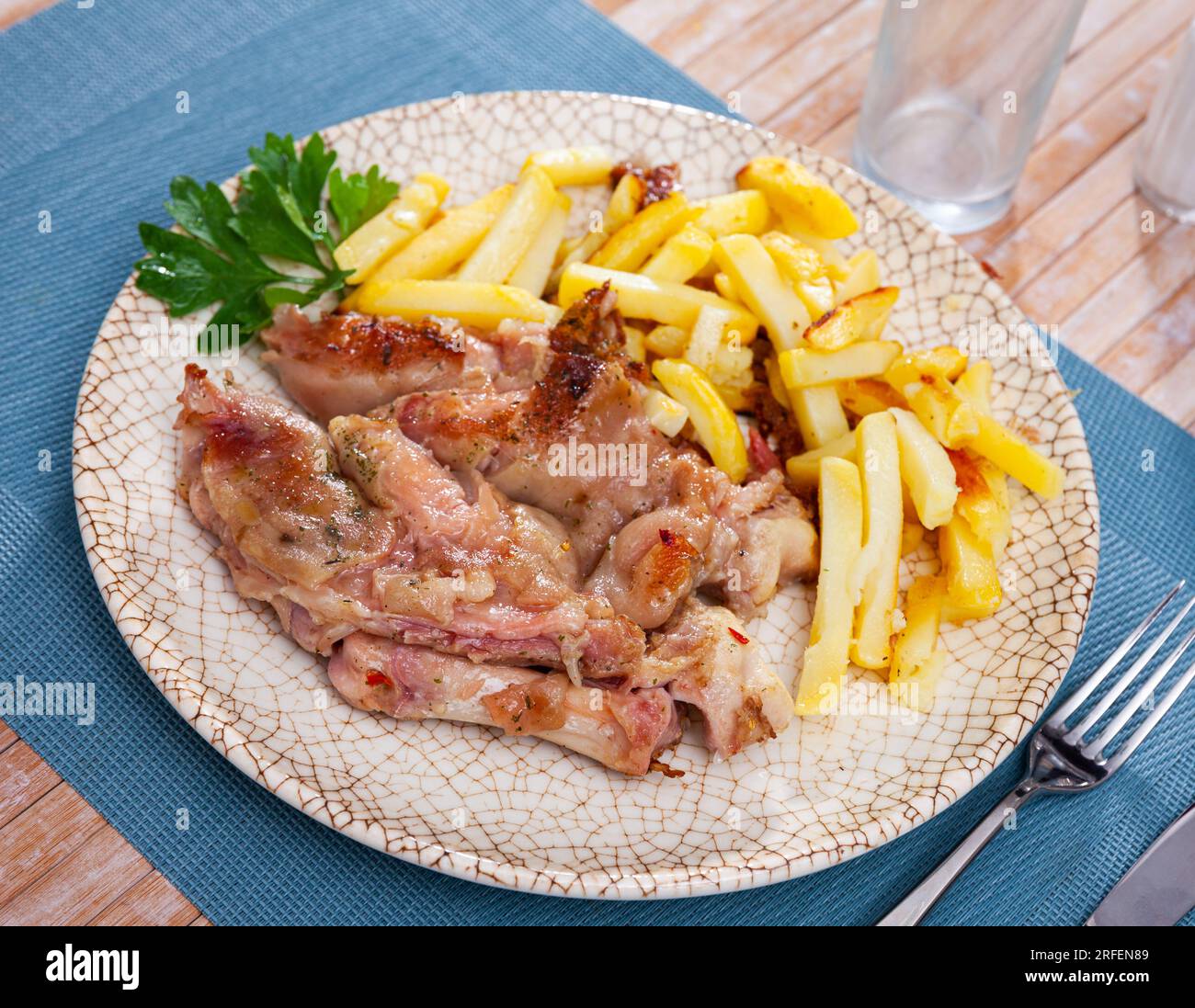 Baked spicy pig trotters with french fries and parsley Stock Photo - Alamy