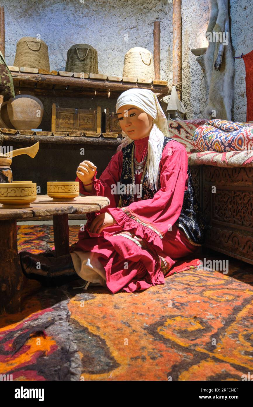A diorama of a traditional Kazakh woman, sitting at home at a low table ...