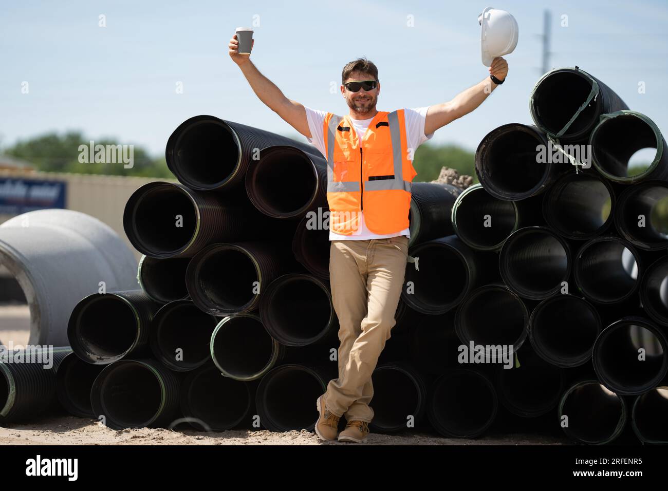 Worker in helmet on break near sewerage pipes. Builder at the ...