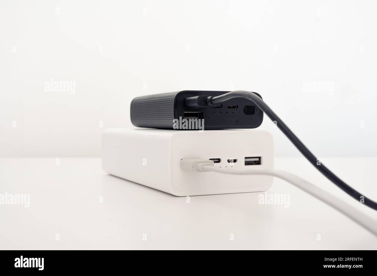 White power bank under black mobile charger with white and black cord ...