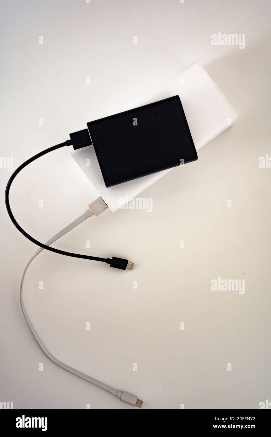 Black power bank on white mobile charger with white and black cord ...