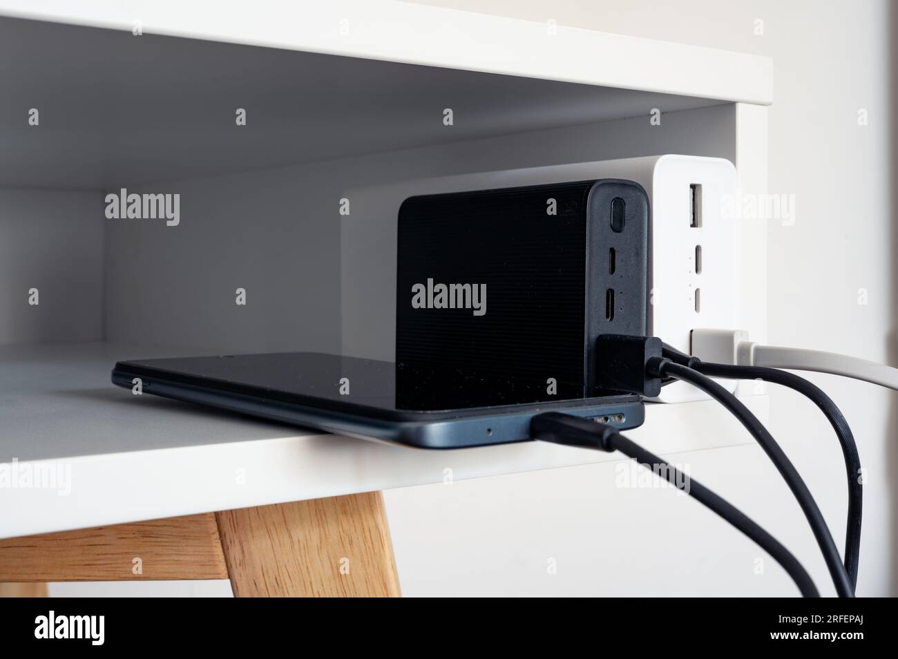 Black power bank charges smartphone. Near it stands white power bank ...