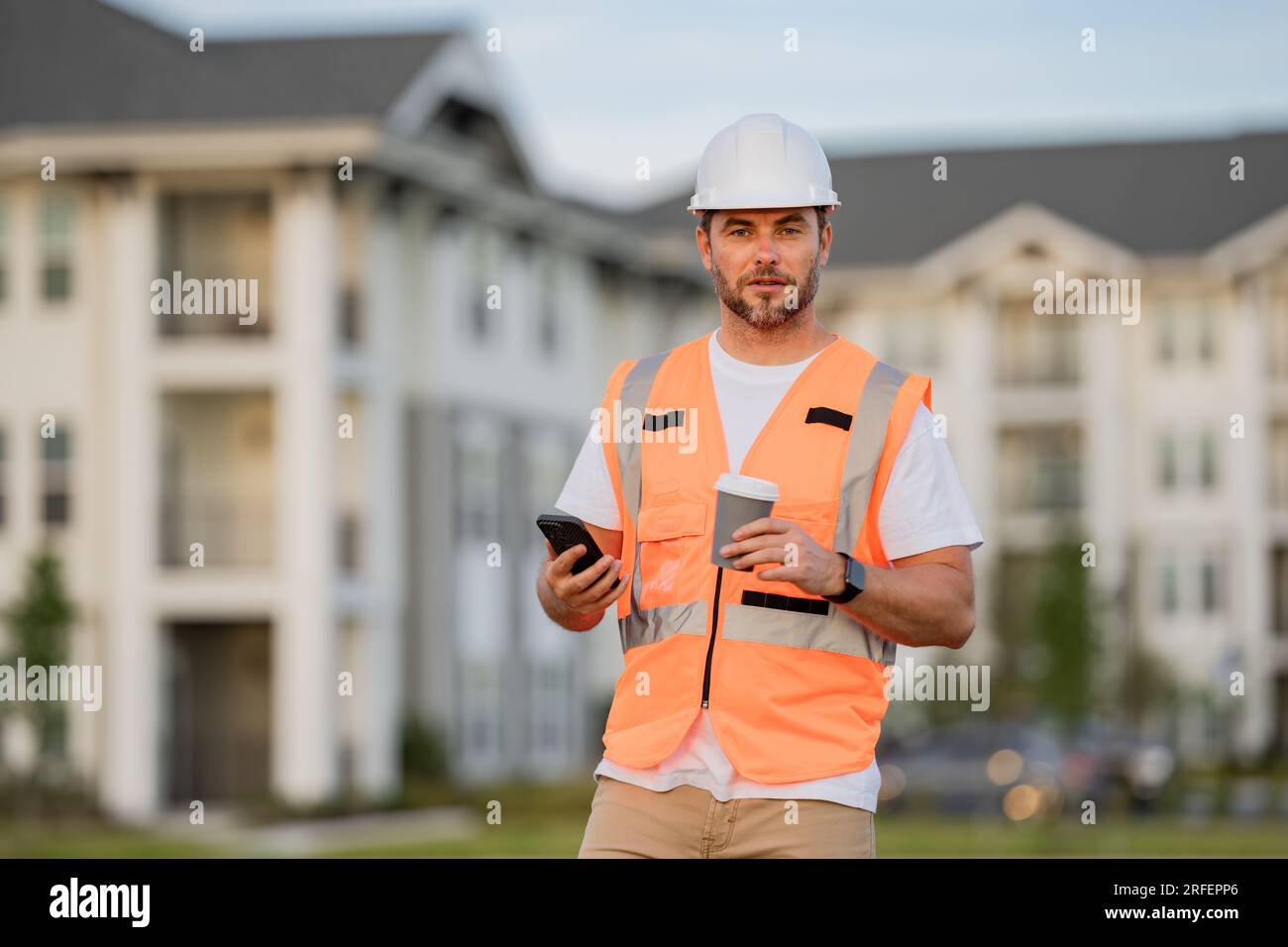 Engineer builder drinking take away coffee using phone on break ...