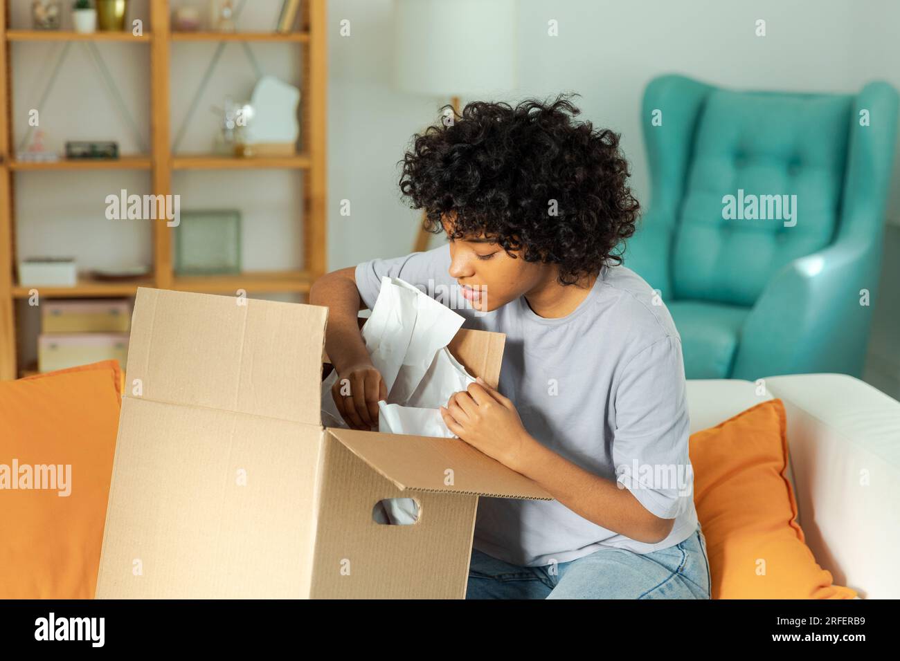 African girl unpacking delivery looking in box. Happy woman opening ...
