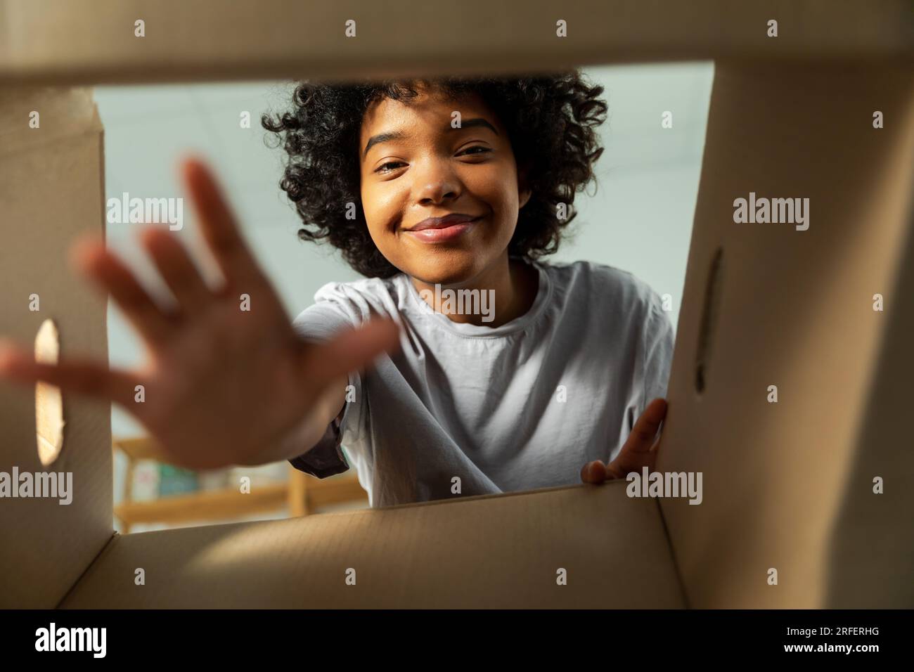 Inside of cardbox bottom view. African girl unpacking delivery looking ...
