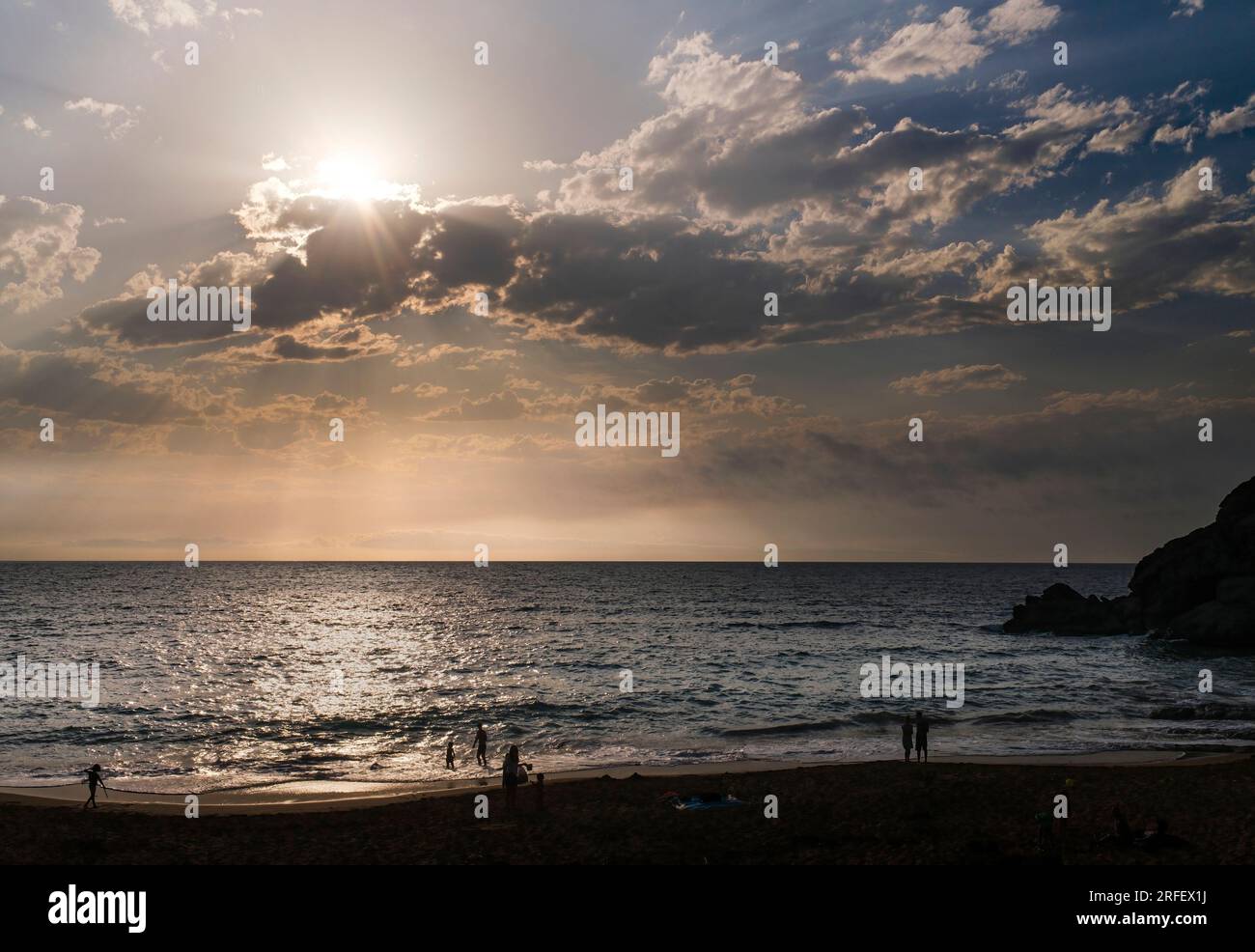 View of a beach in Cantabria at sunset with the sun through the clouds ...