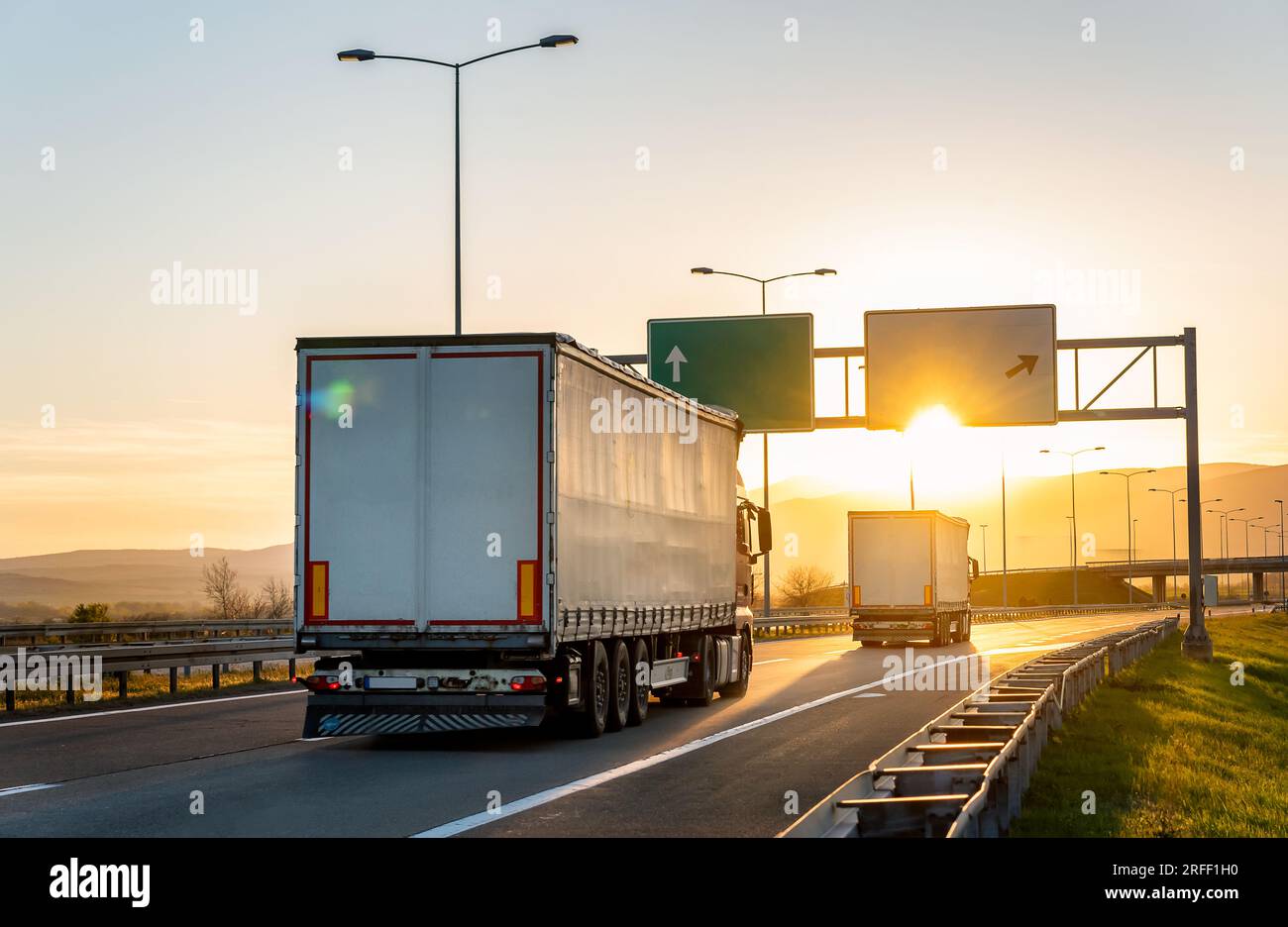 Rear angle view of delivery cargo trucks on the road going to the west ...