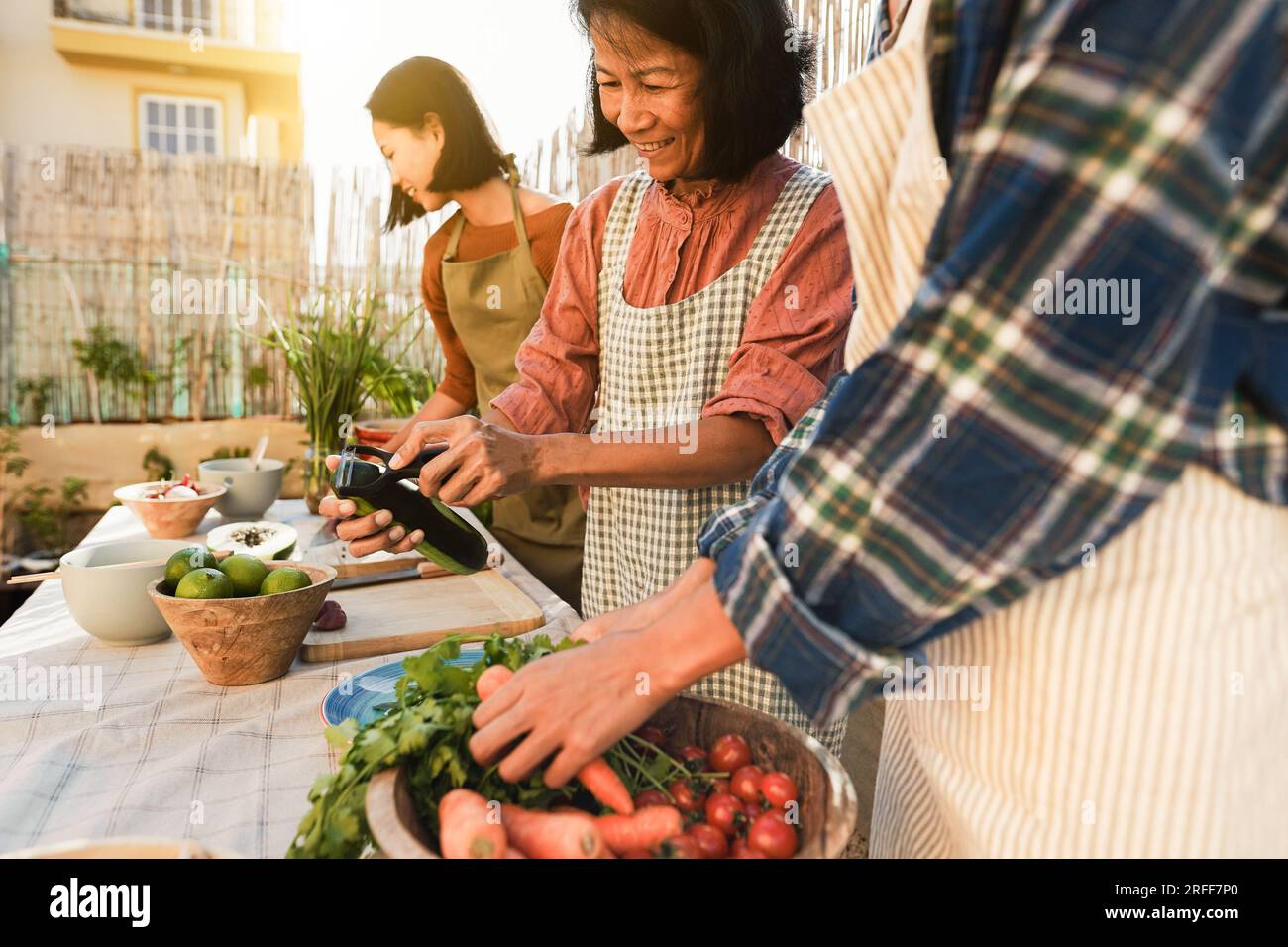 Asian family cooking together at home patio outdoor - Mother and two ...