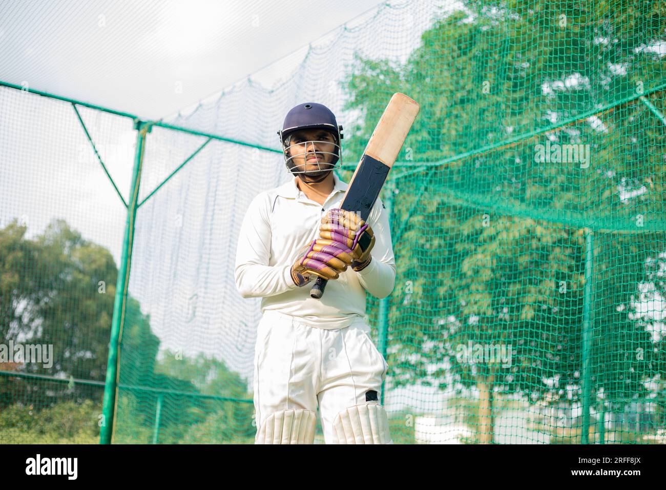 cricket player is ready to practice batting in the nets during his ...
