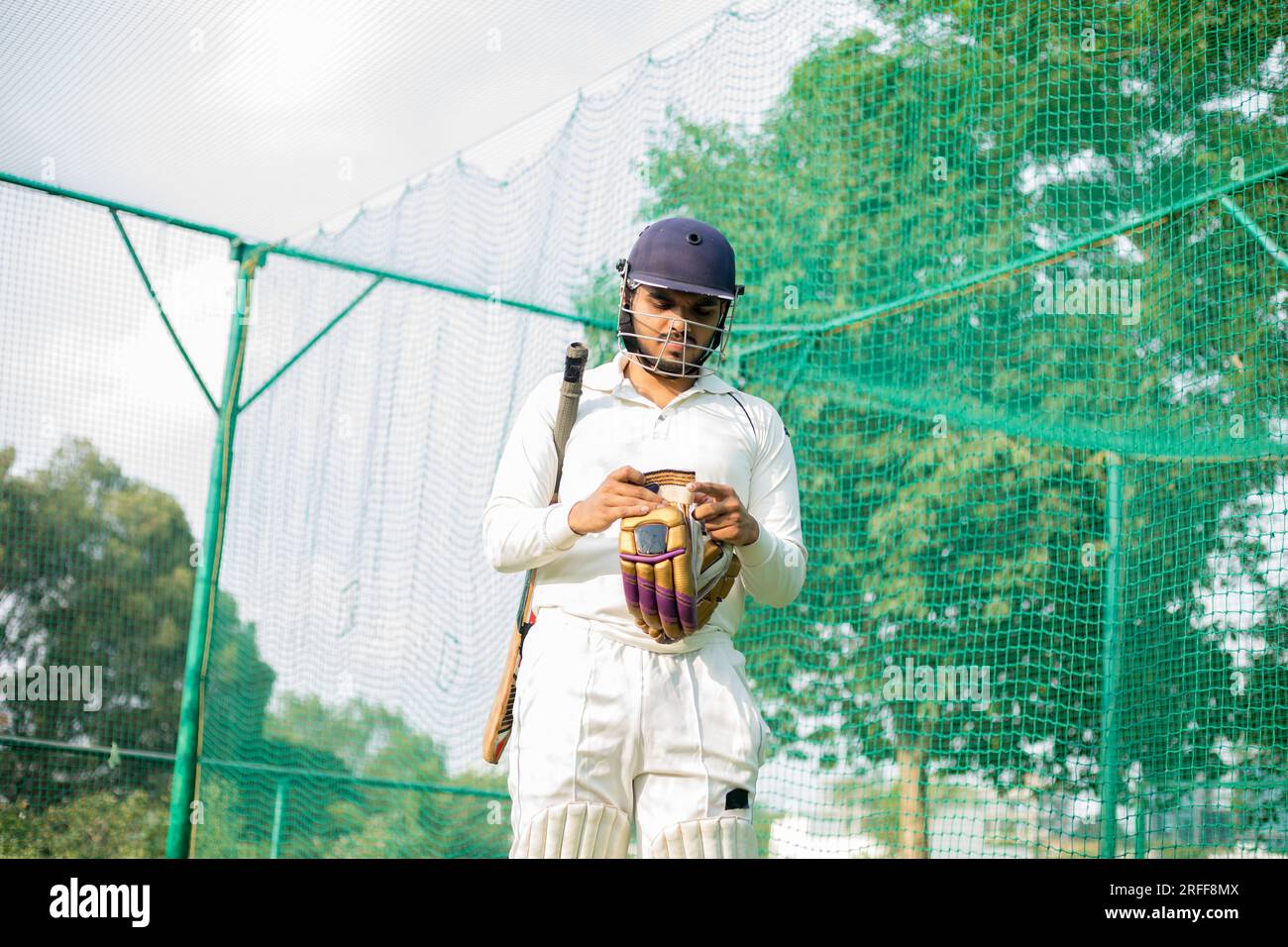 Cricket player wearing hand gloves to do practice in cricket nets Stock Photo - Alamy