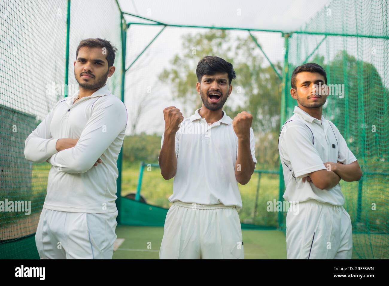 Cricket players standing a giving team poses in cricket nets at ...