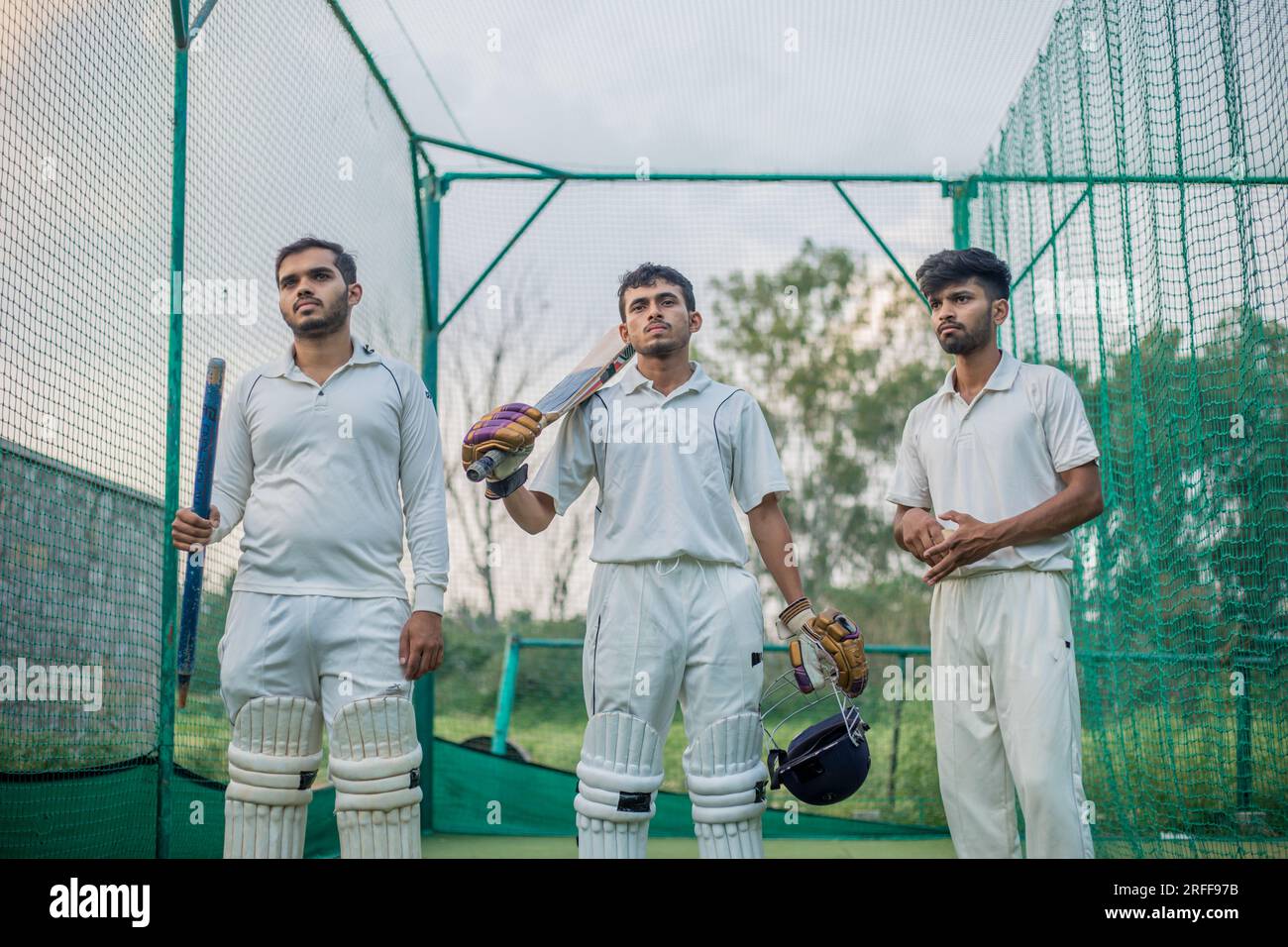 Cricket players standing a giving team poses in cricket nets in ...