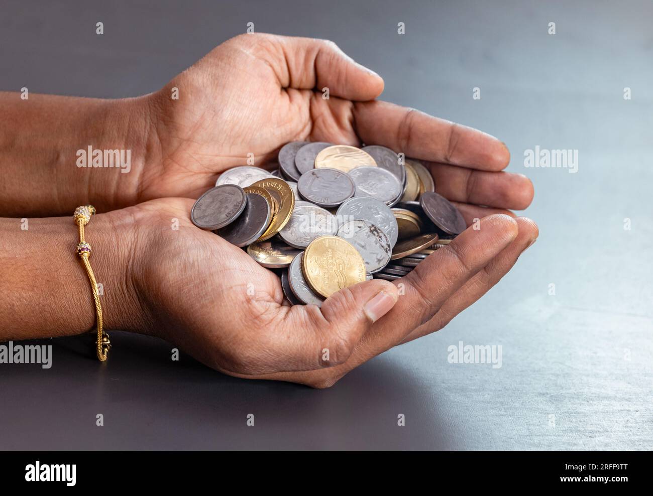 A close-up of a hand holding a large handful of Indian coins Stock ...