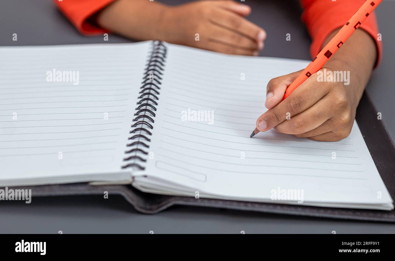 A close-up photo of a young kid, writing in a notebook. He is left ...