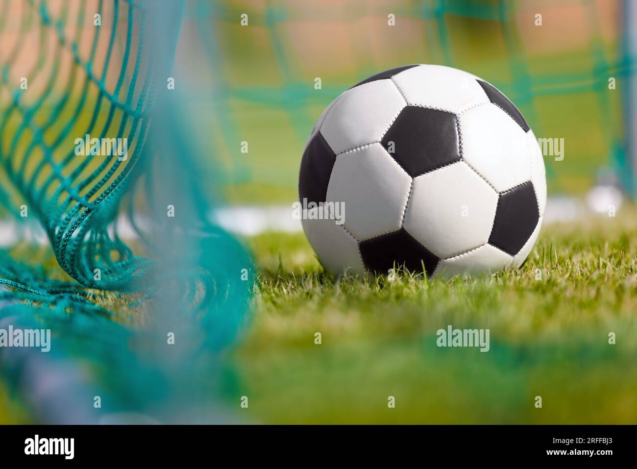 Classic football (soccer) ball on green grass ground at the back of the ...