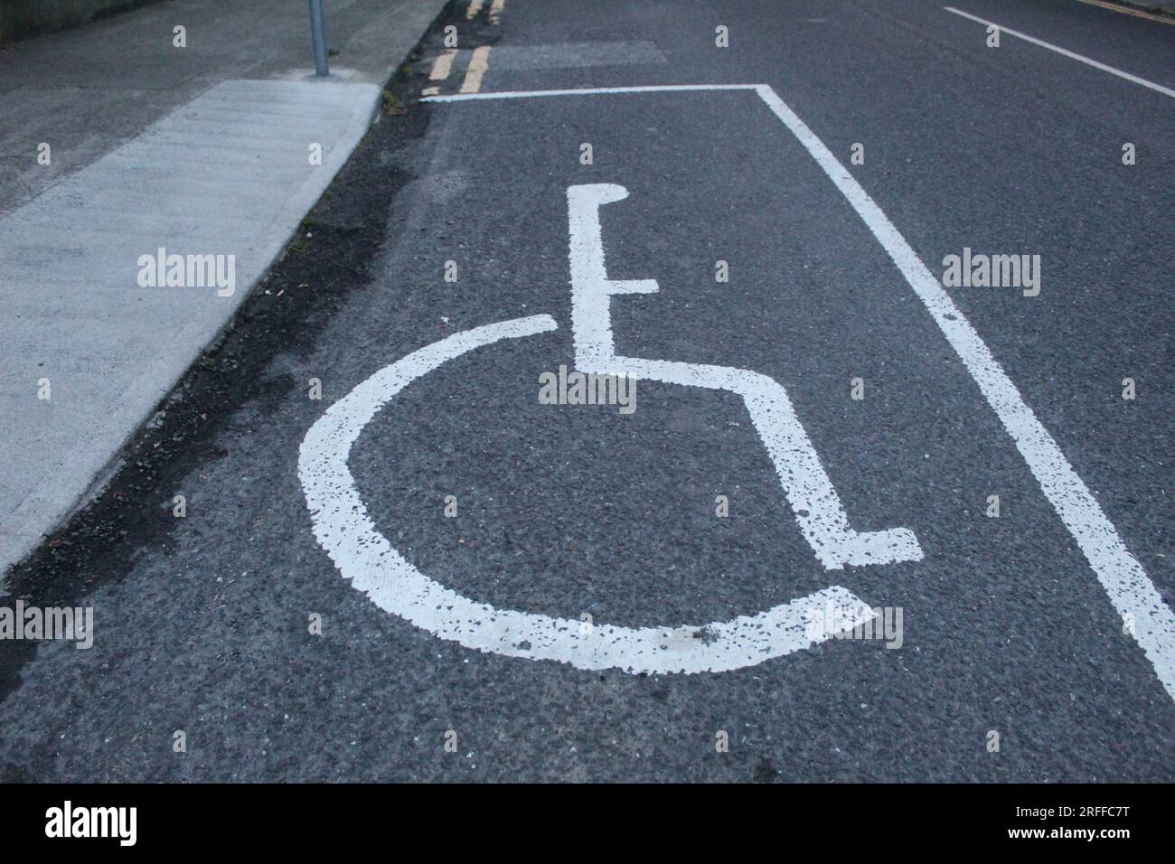 A photo of a disabled persons parking spot sign on a road surface Stock ...