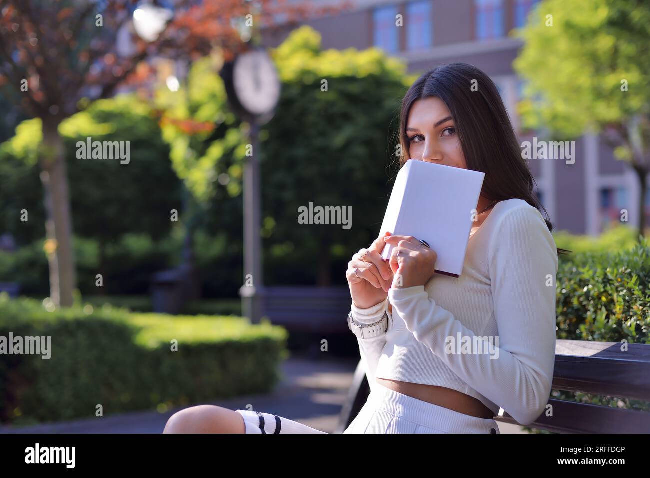 Portrait of a pretty lady with brown eyes holds white blank-covered ...