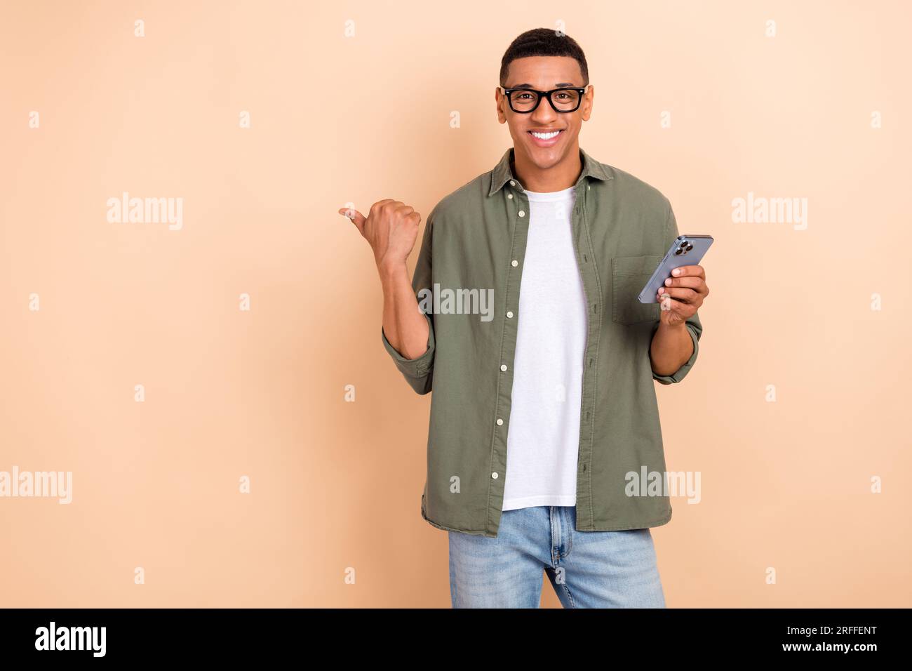 Portrait of handsome guy hold smart phone direct finger empty space ...